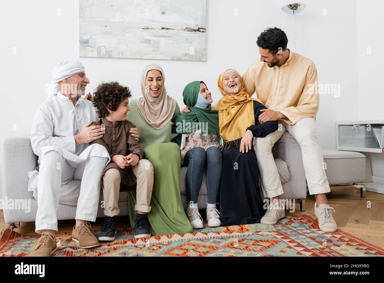 joyful multicultural muslim family laughing on sofa at home Stock Photo ...