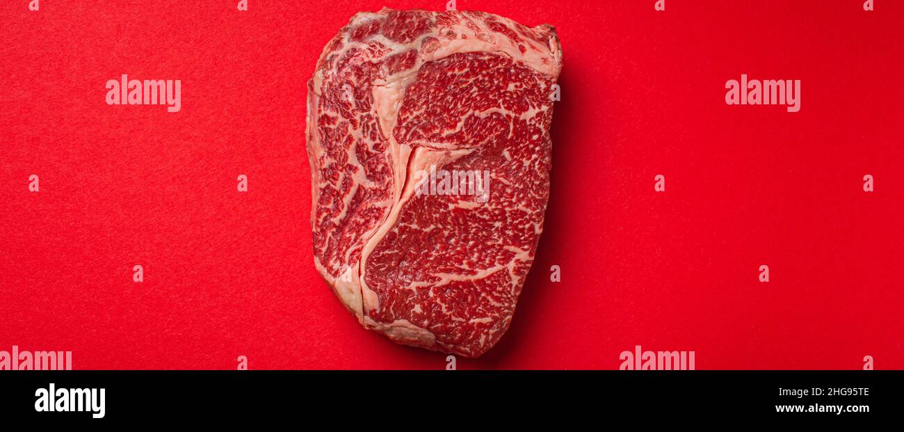 Raw meat beef prime cut steak Ribeye on clean red background from above ...