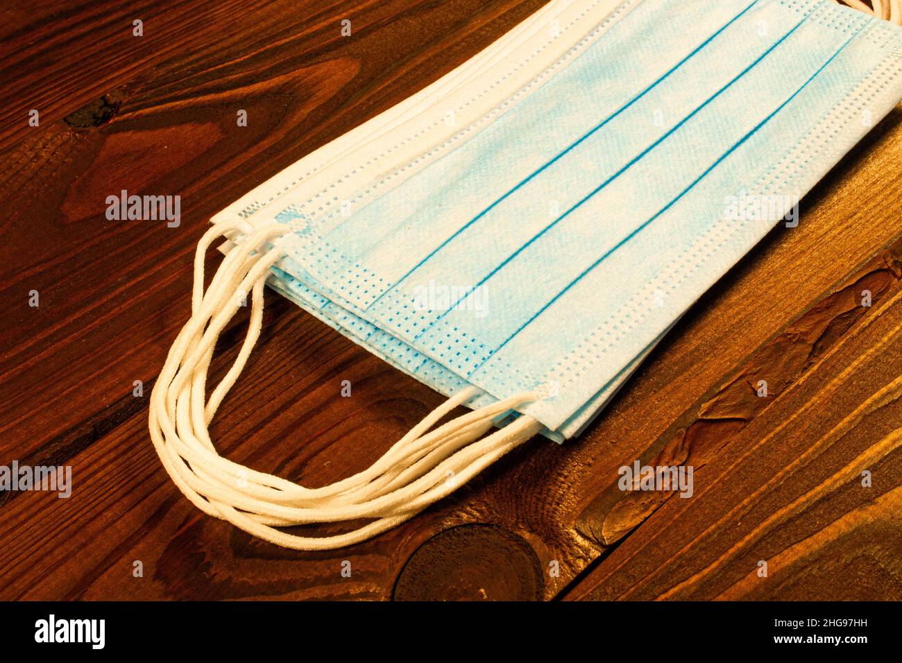 Blue medical disposable face masks on a brown wooden table. Lots of ...