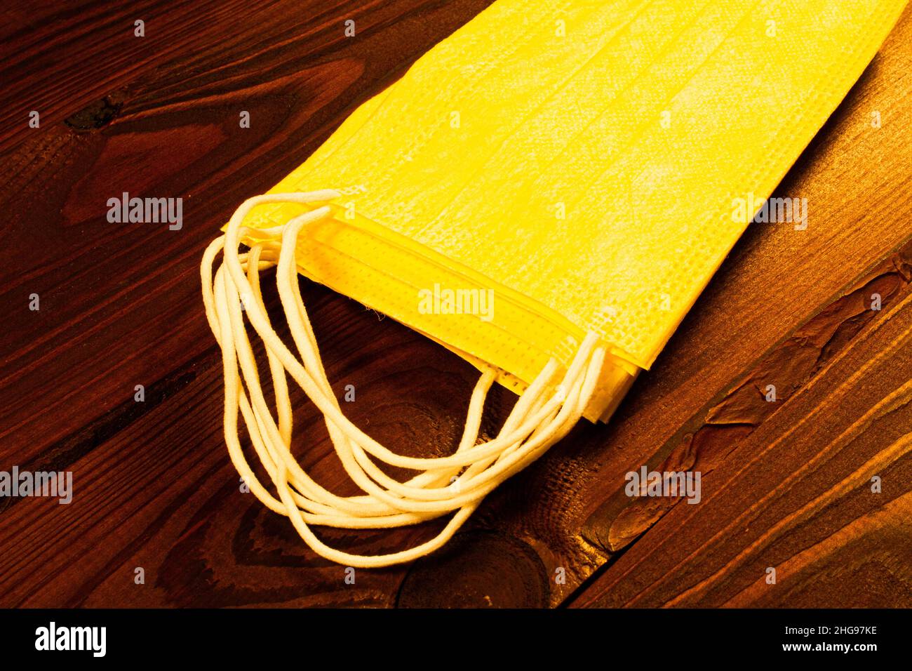 Yellow medical disposable face masks on a brown wooden table. Lots of ...