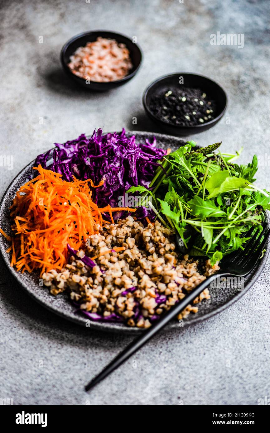 Close-Up of a plate with buckwheat, carrot, red cabbage, rocket with ...