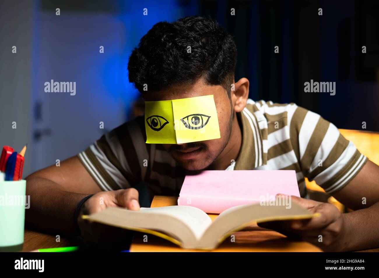 Young student acting like reading while sleeping by putting eye open ...