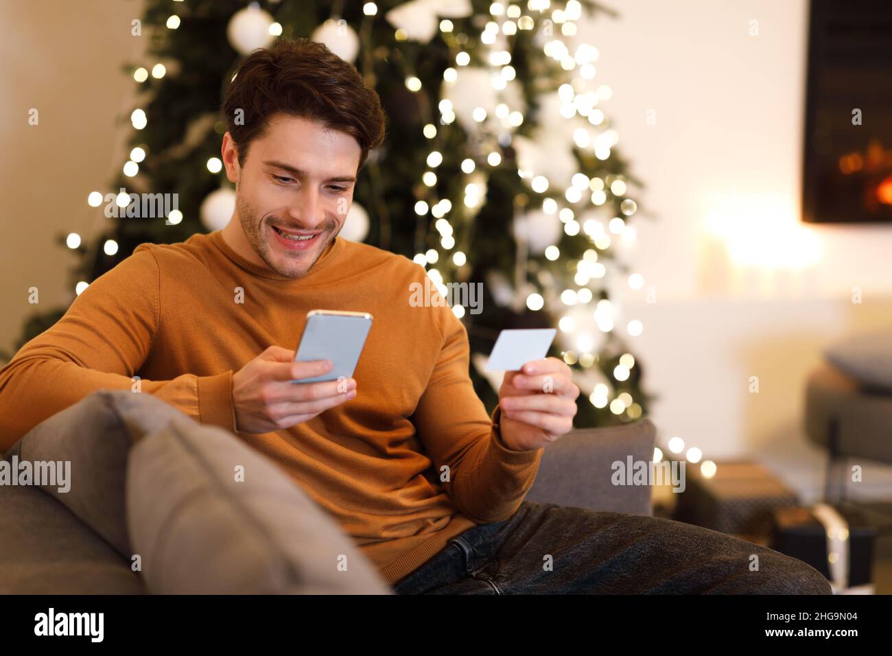 Smiling man holding debit credit card, using mobile phone Stock Photo ...