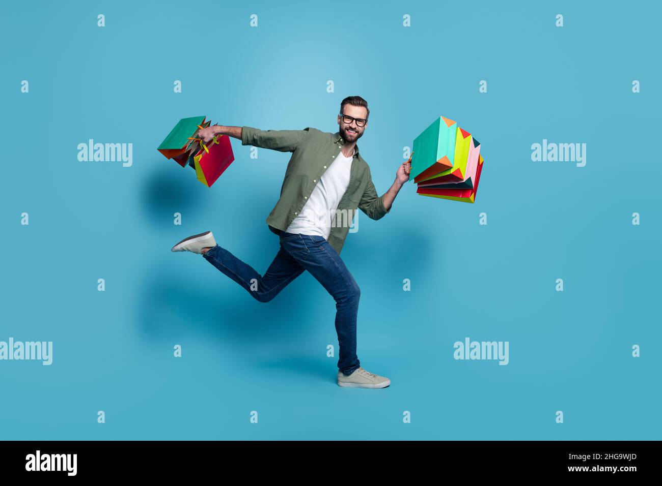 Photo of sporty handsome guy jump carry outfit packages run wear specs ...