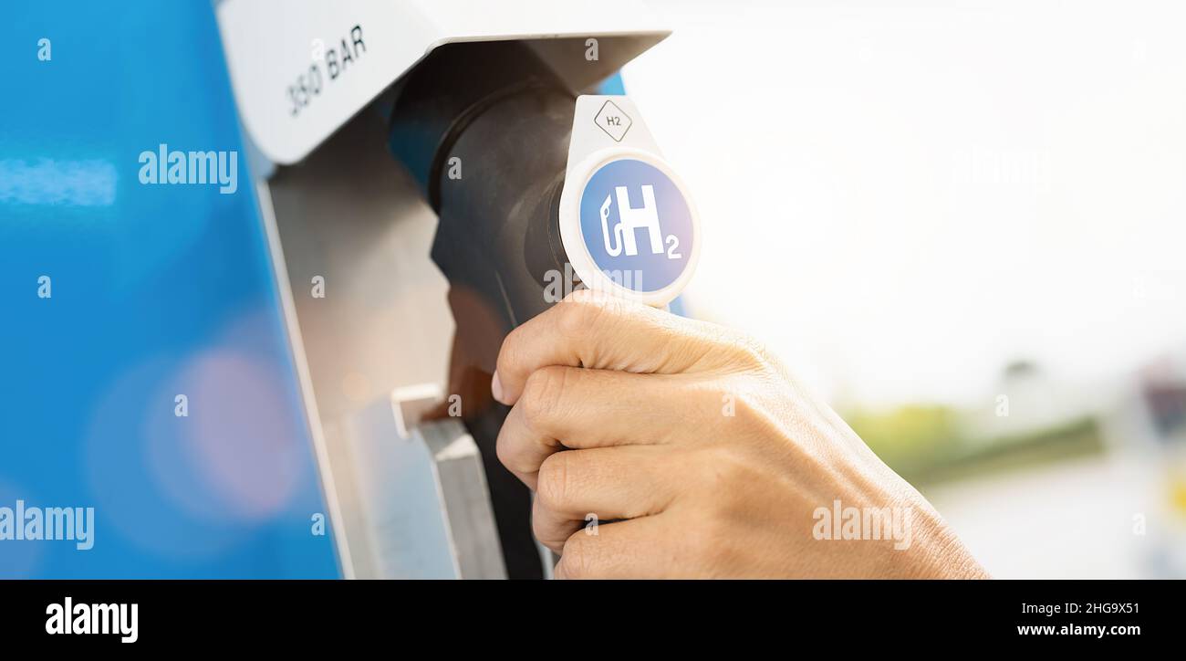 Woman hold a fuel dispenser with hydrogen logo on gas station. h2 ...