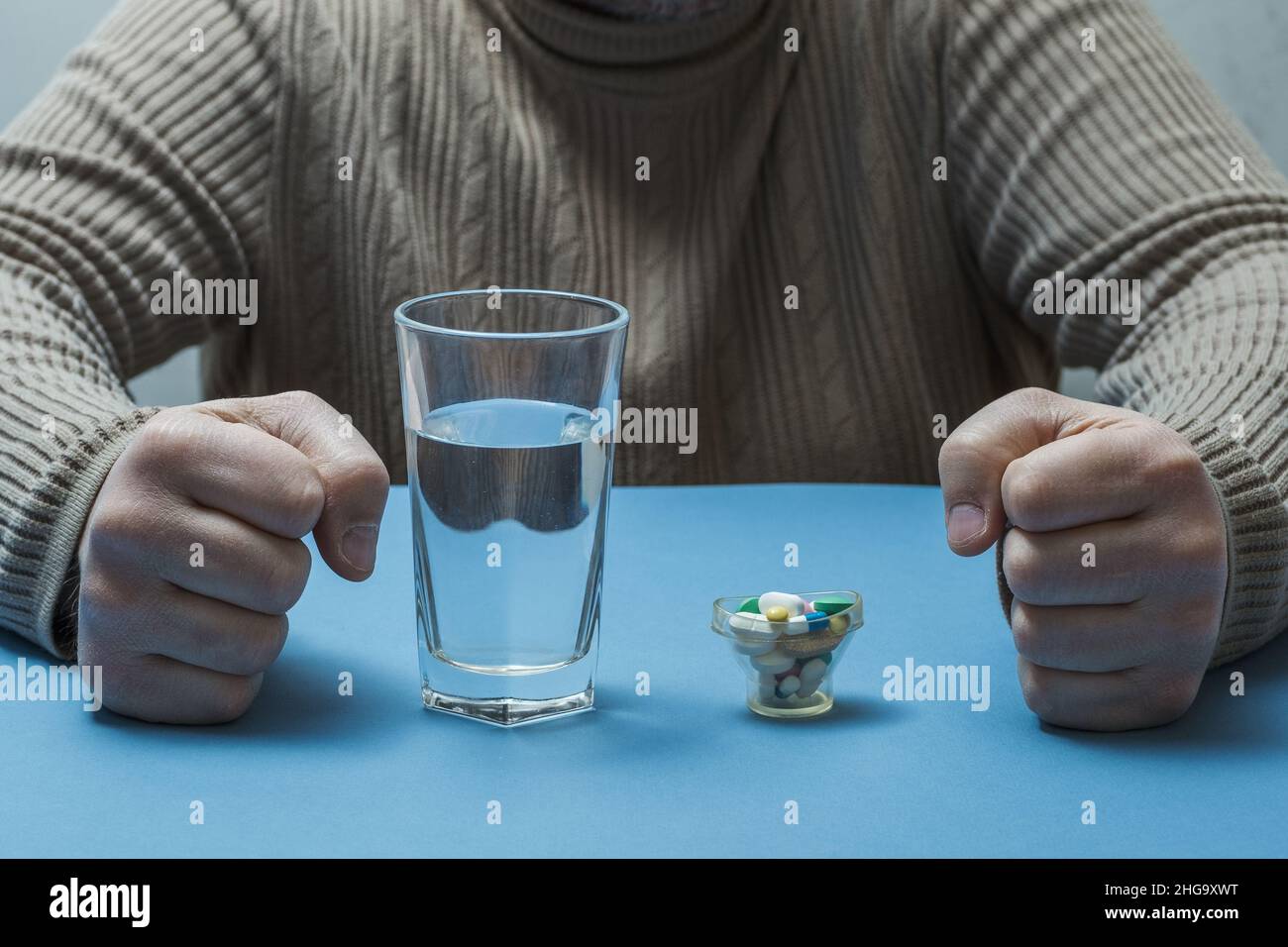 Man clenches his hands into fists, medical preparations and a glass of ...