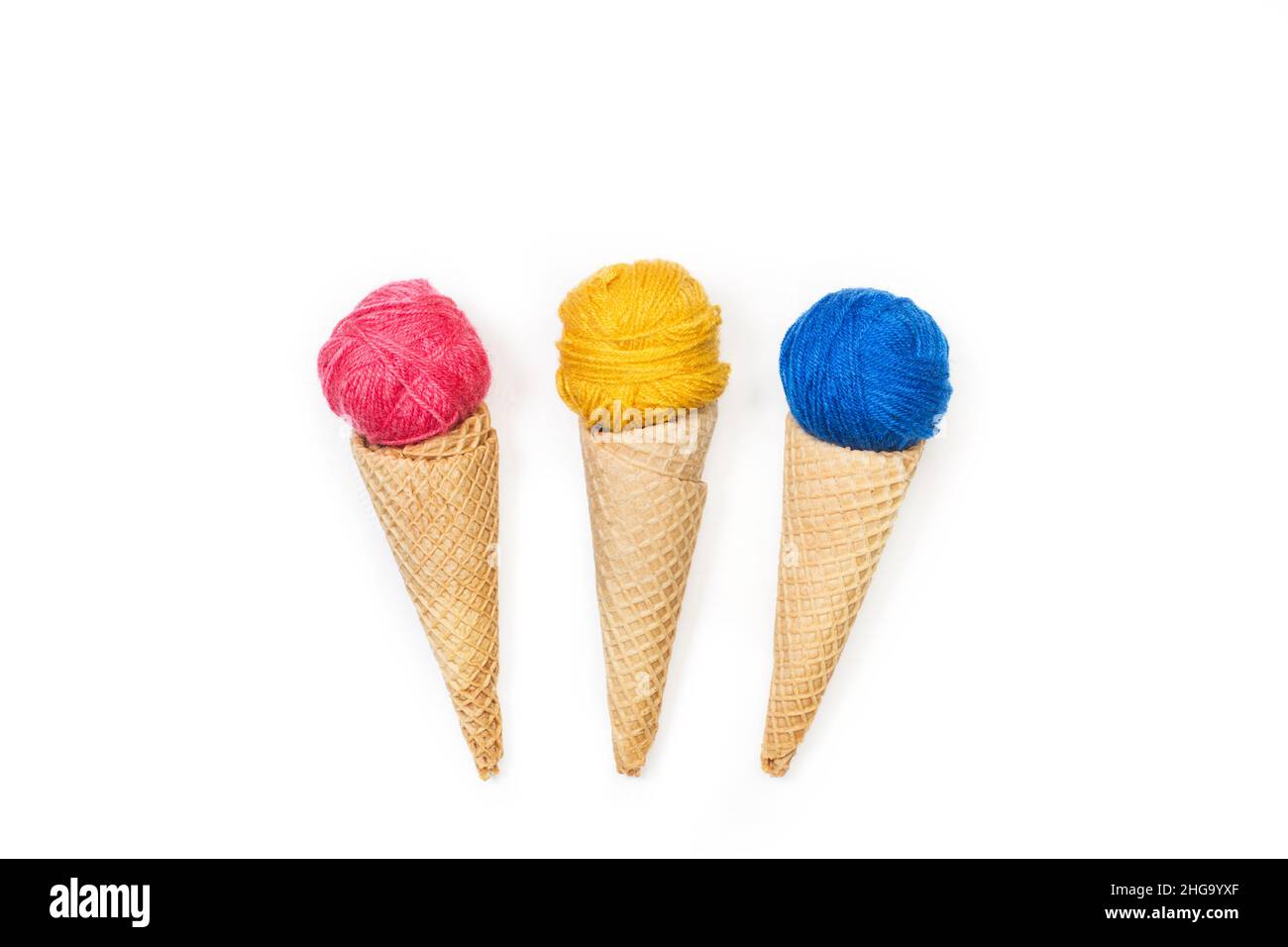 Colored wool balls on wafer cones ice cream shape on a white background ...