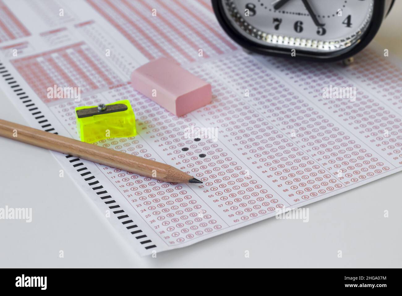 Alarm clock,wooden pencil and rubber on filled exam sheet,conceptual ...