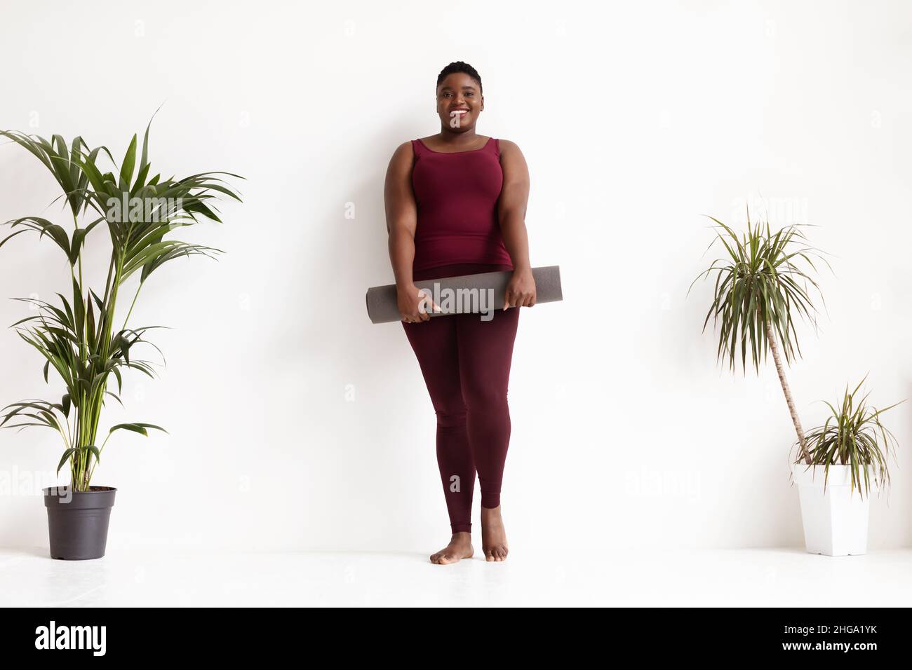 Cheerful attractive overweight young black woman posing with fitness ...