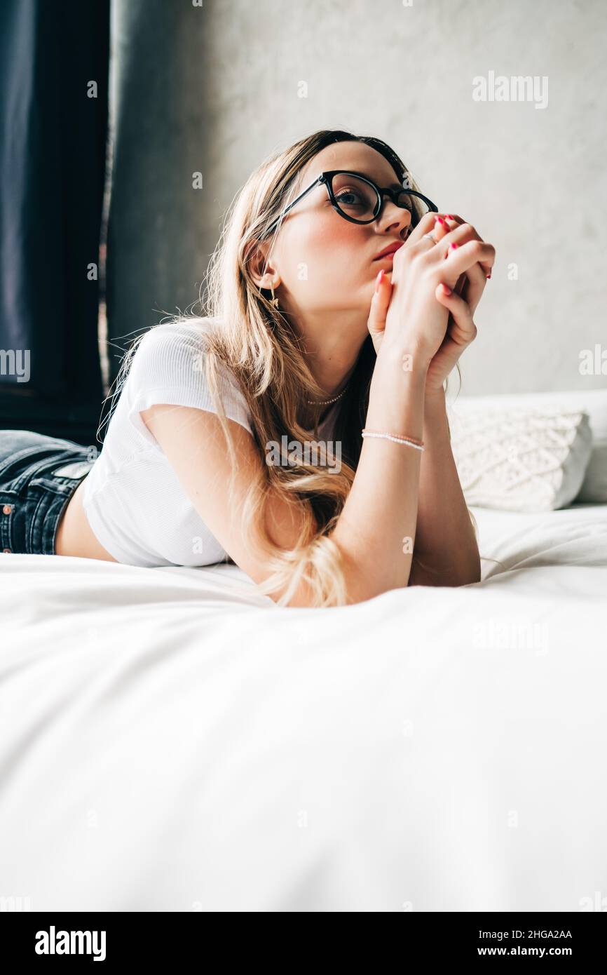 Young bored millennial woman lying on a bed alone at home. Fatigue or ...