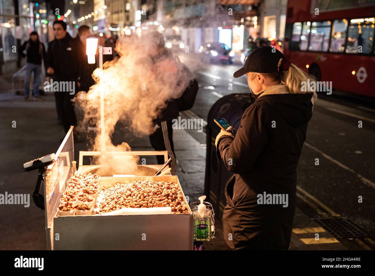 London, UK. January 14th 2022. A street merchant looks at her ...
