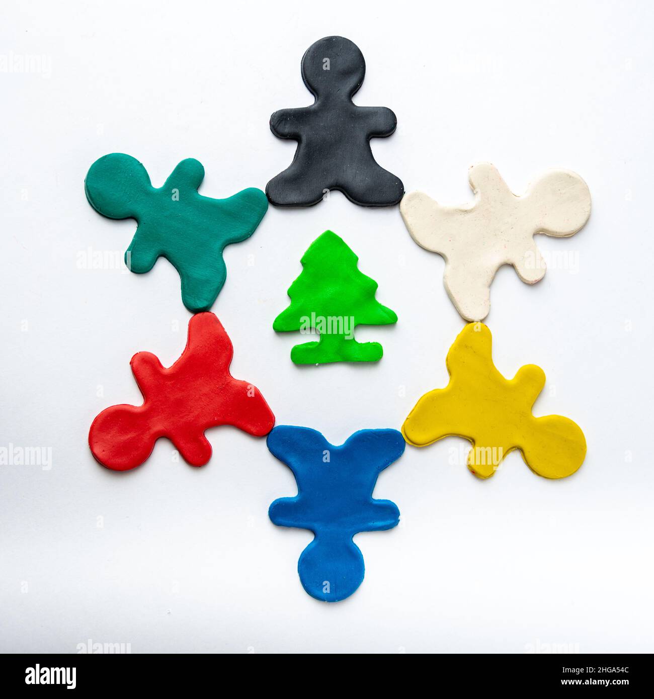 Multicolored bright plasticine men in a circle in the center of a green ...