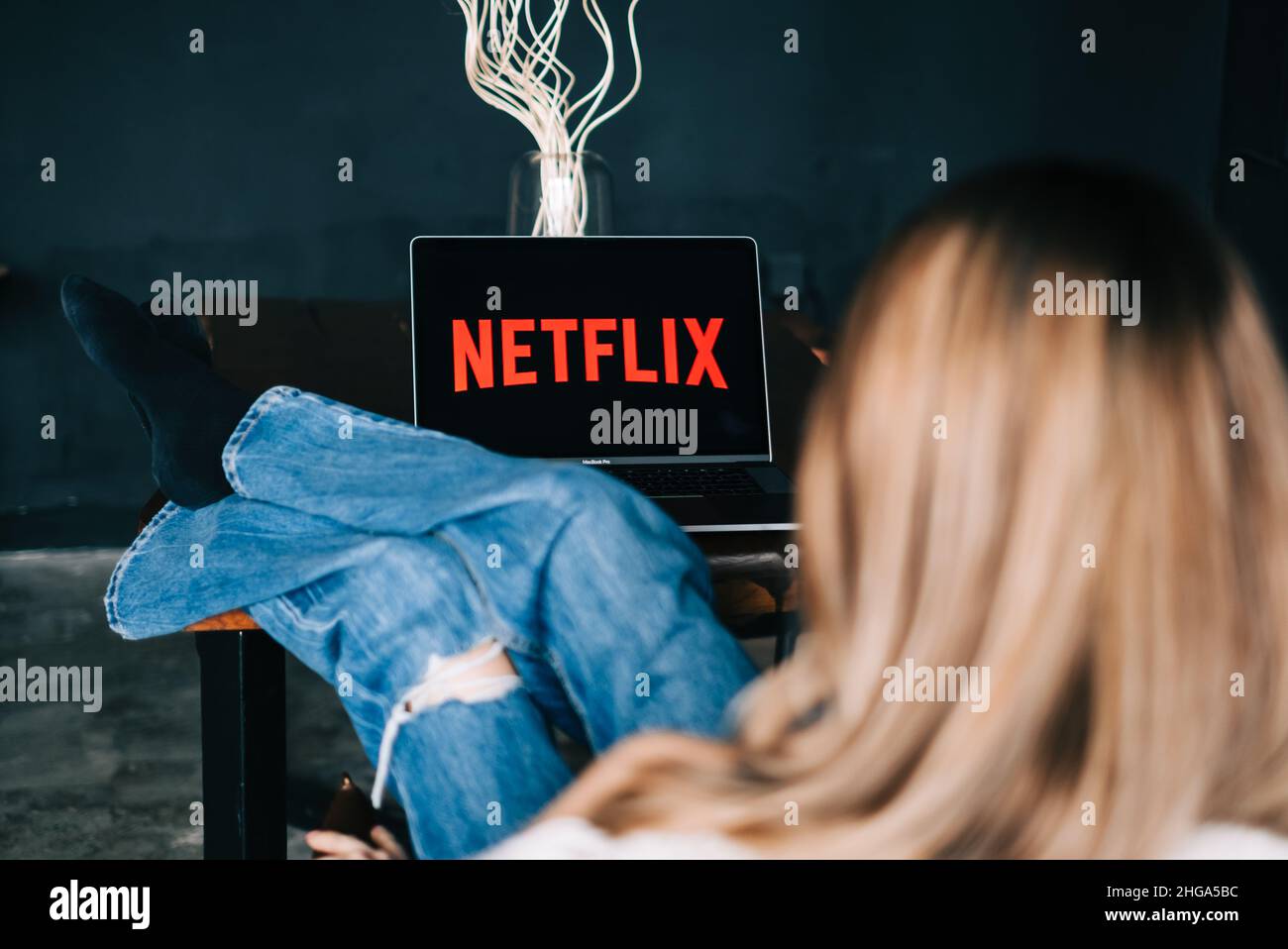 Netflix logo on the laptop screen. Young woman watching netflix channel ...