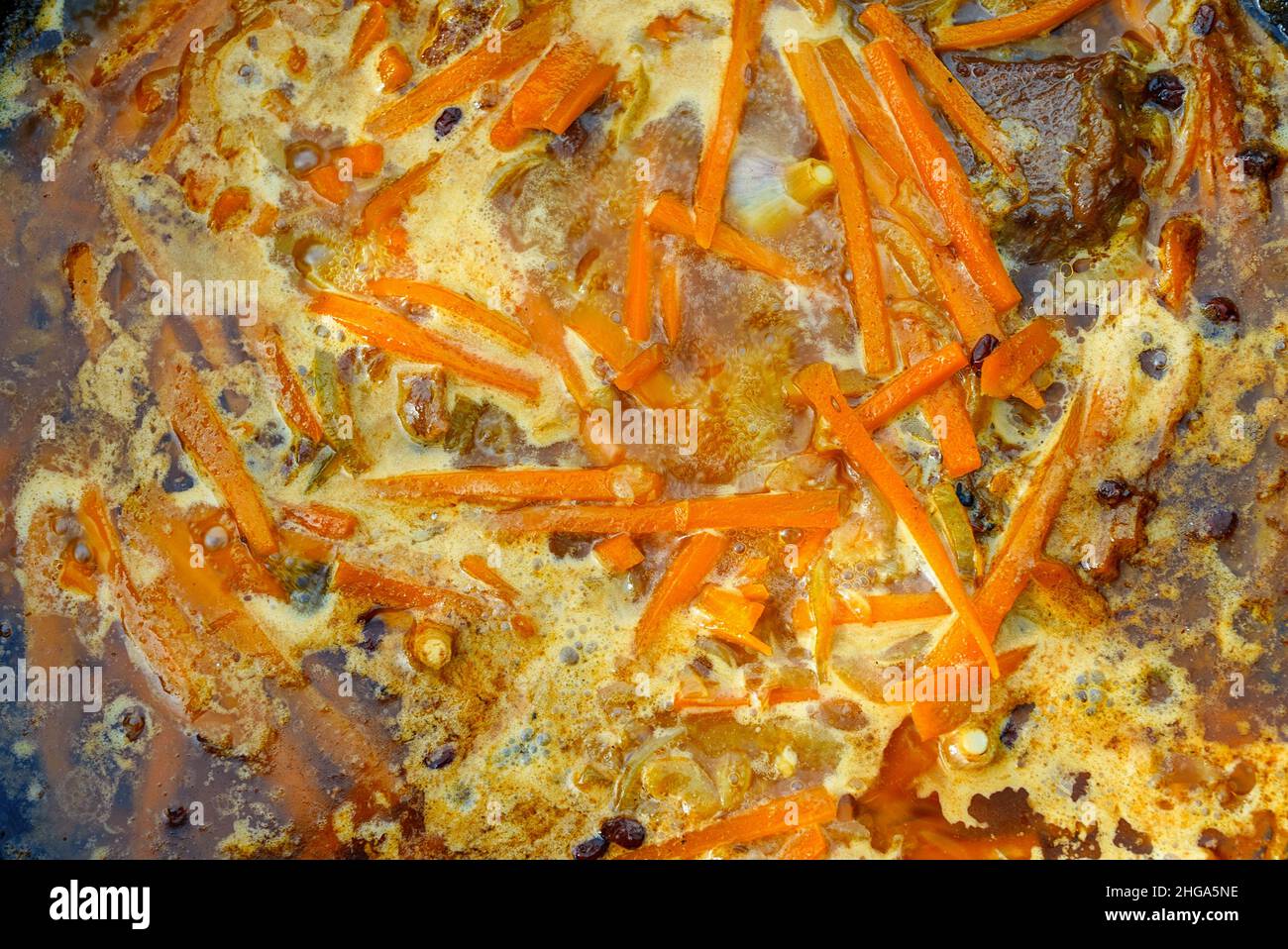 Meat with carrot is cooked in cauldron on fire. Step by step cooking of ...
