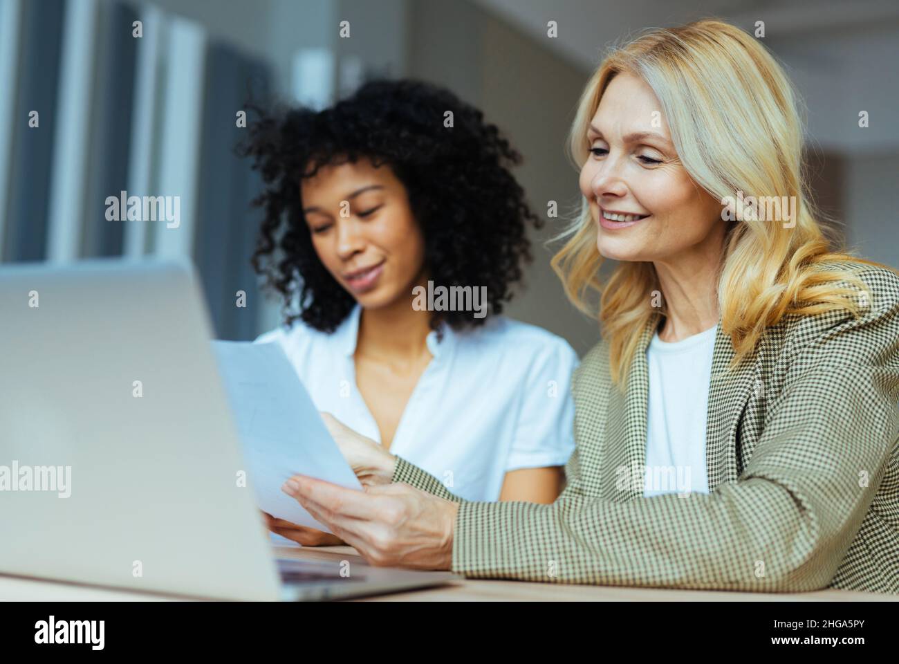 Beautiful adult businesswomen with elegant dress sitting at computer ...