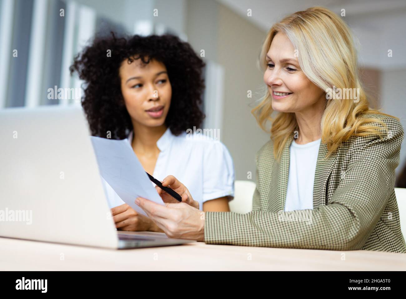 Beautiful adult businesswomen with elegant dress sitting at computer ...