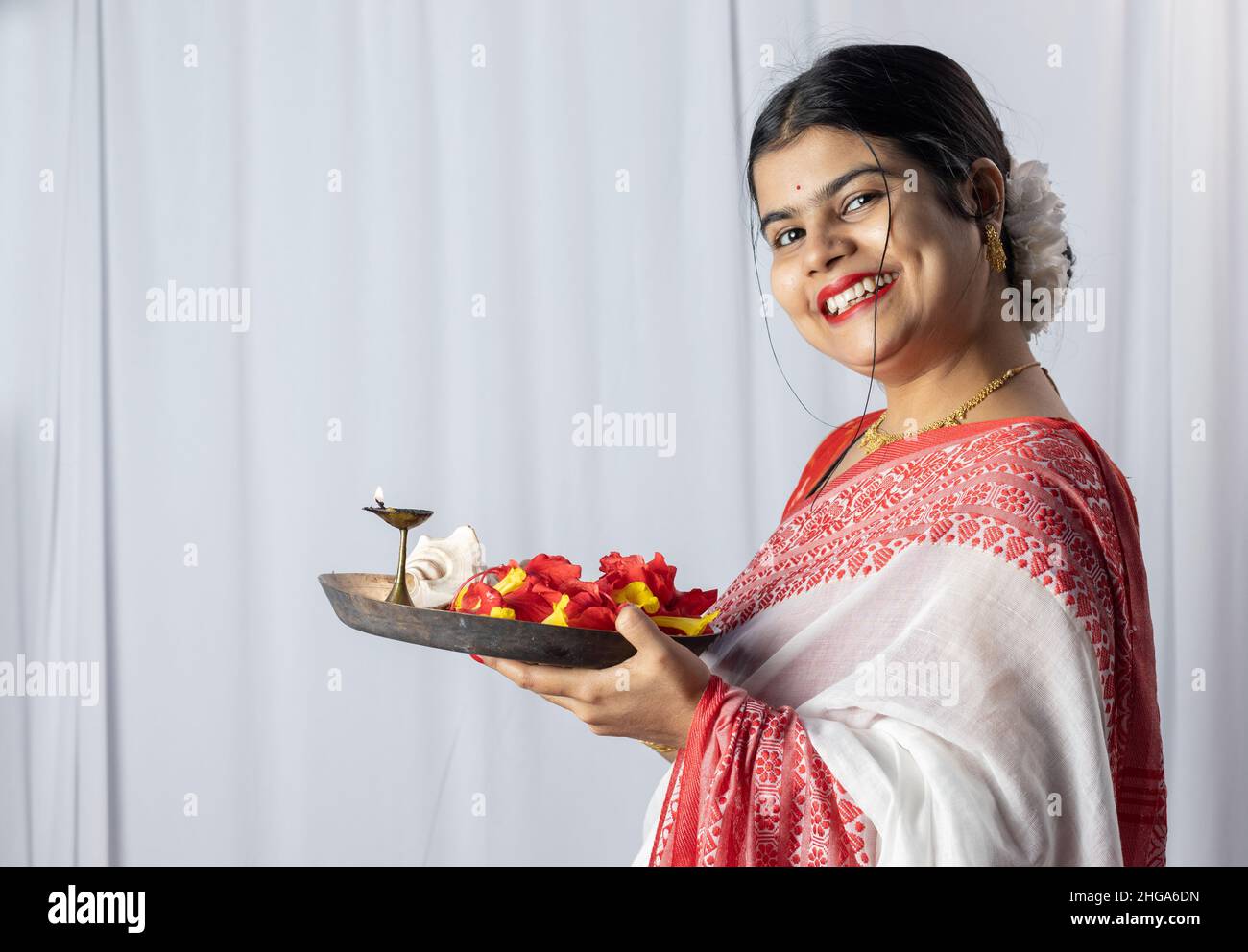 A beautiful Indian woman in red saree holding puja thali or prayer ...
