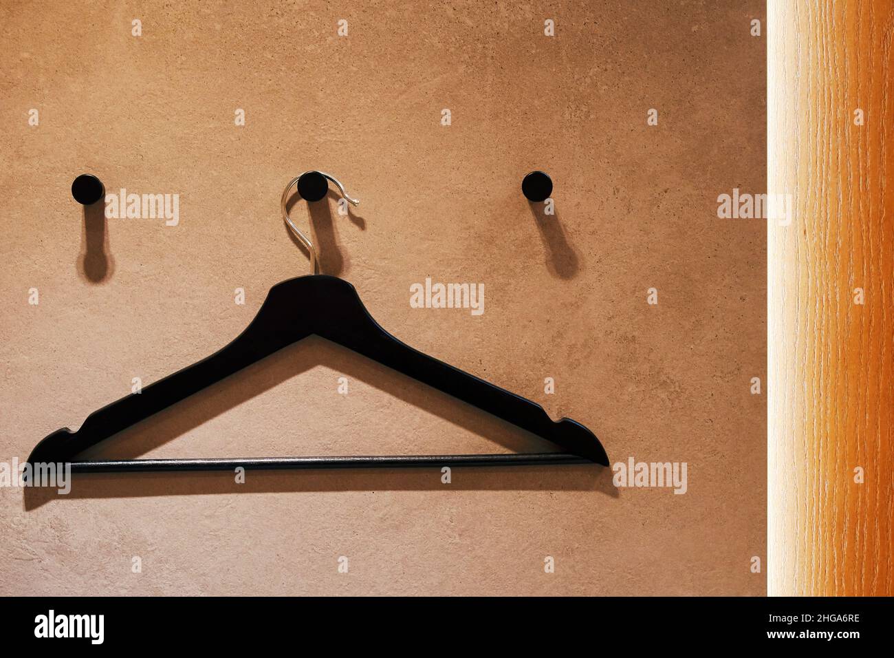 Stylish wooden clothes hanger hanging on a hook. Home interior ...