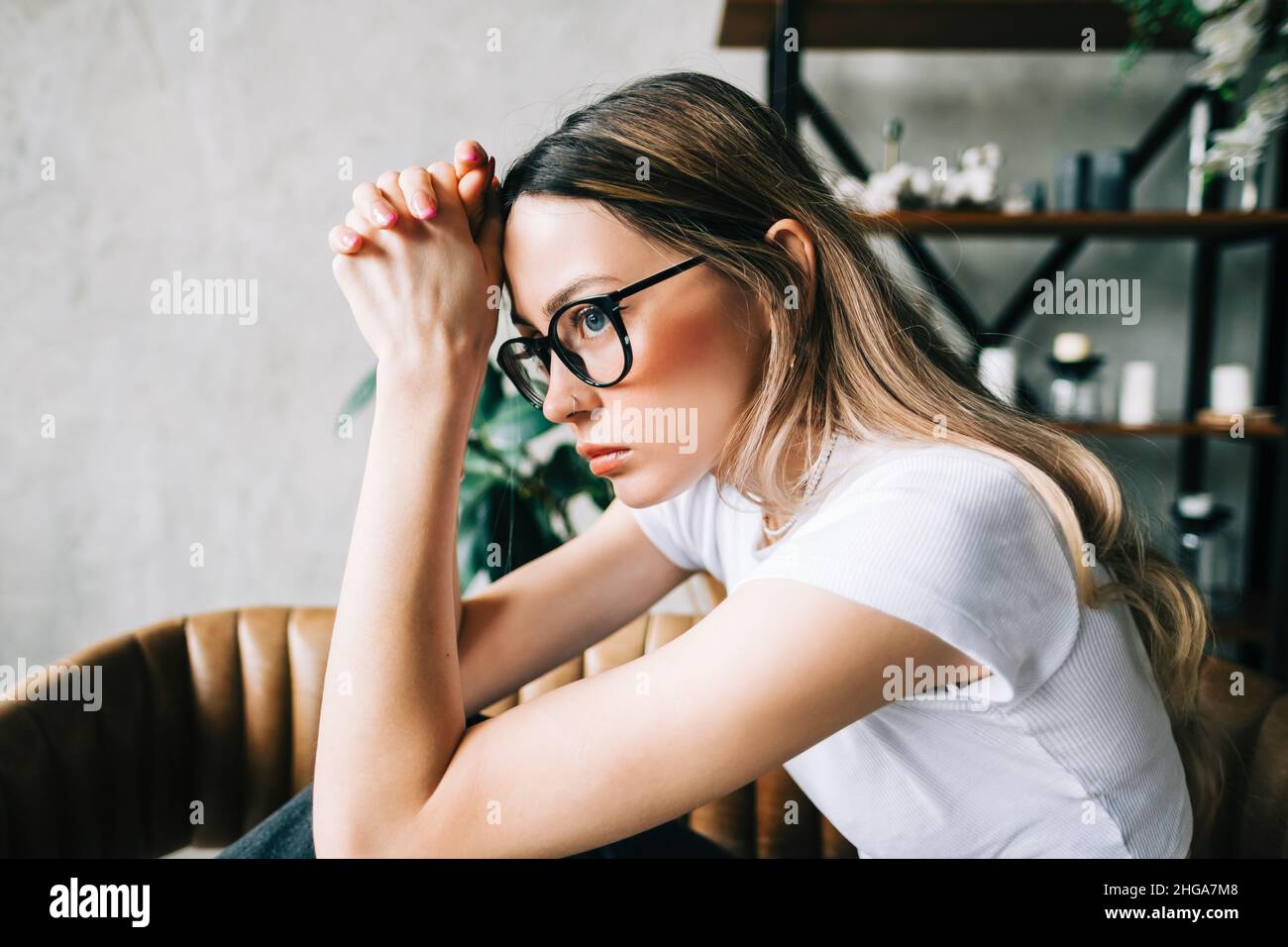 Young bored millennial woman sitting on a sofa alone at home. Fatigue ...