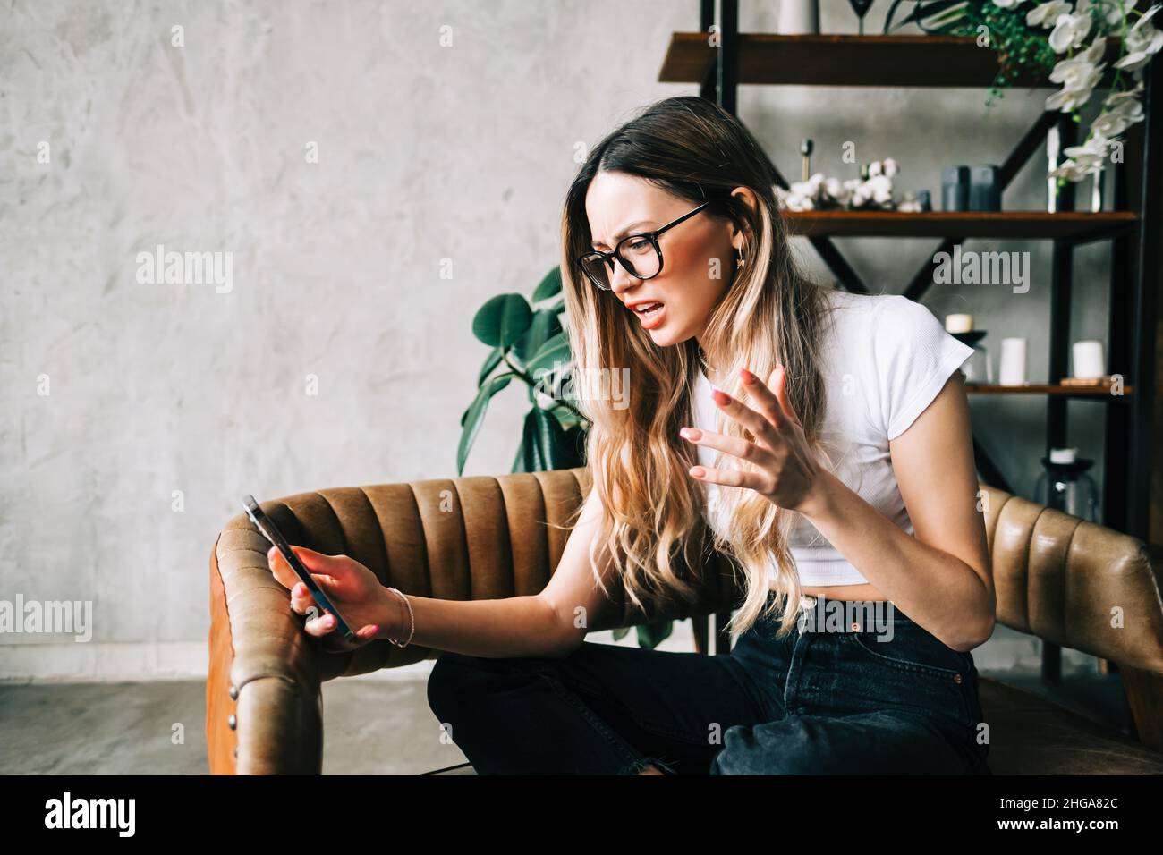 Emotional angry young woman having video call, screaming and gesturing ...