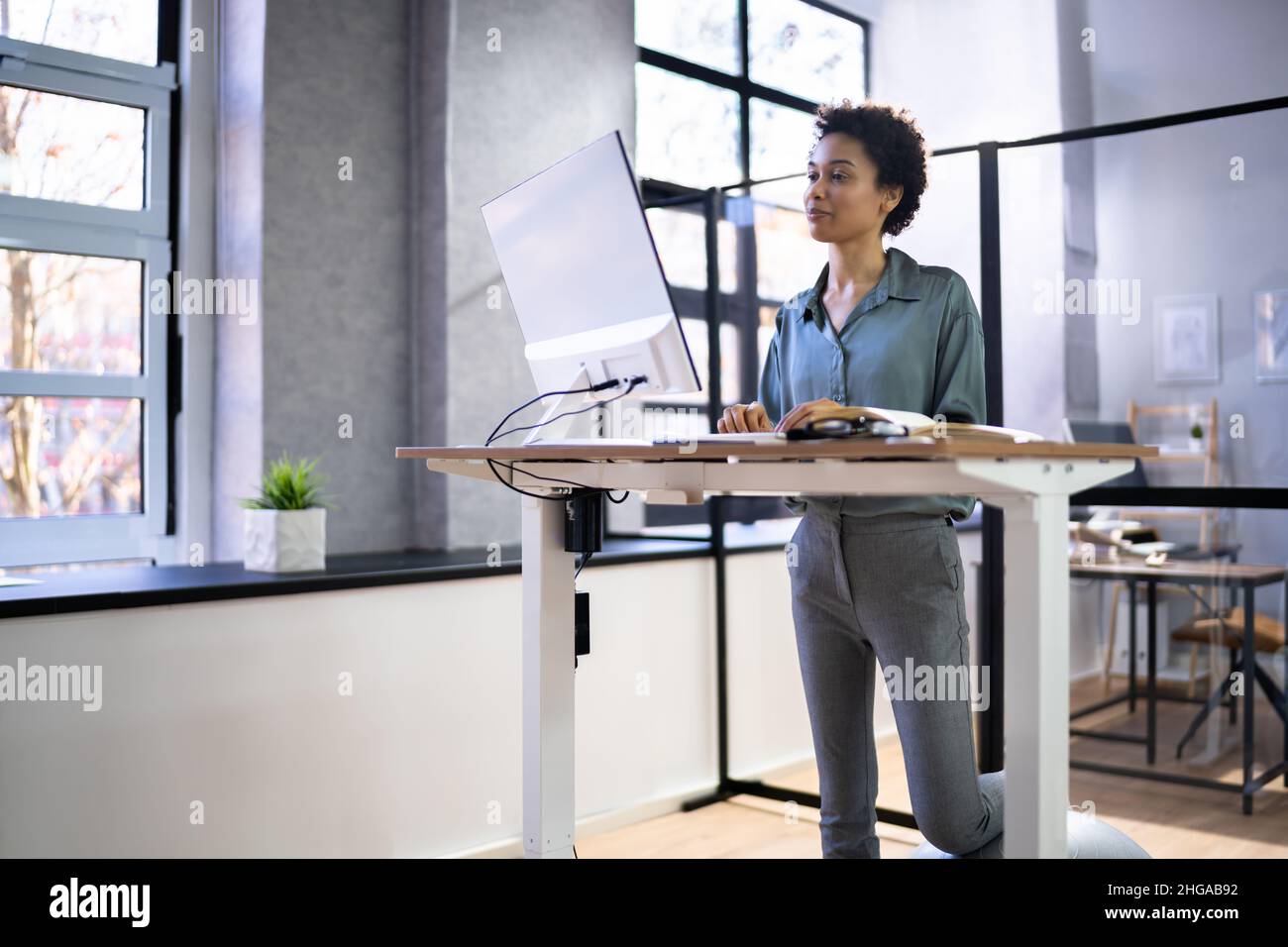 Adjustable Height Desk Stand In Office Using Computer Stock Photo - Alamy