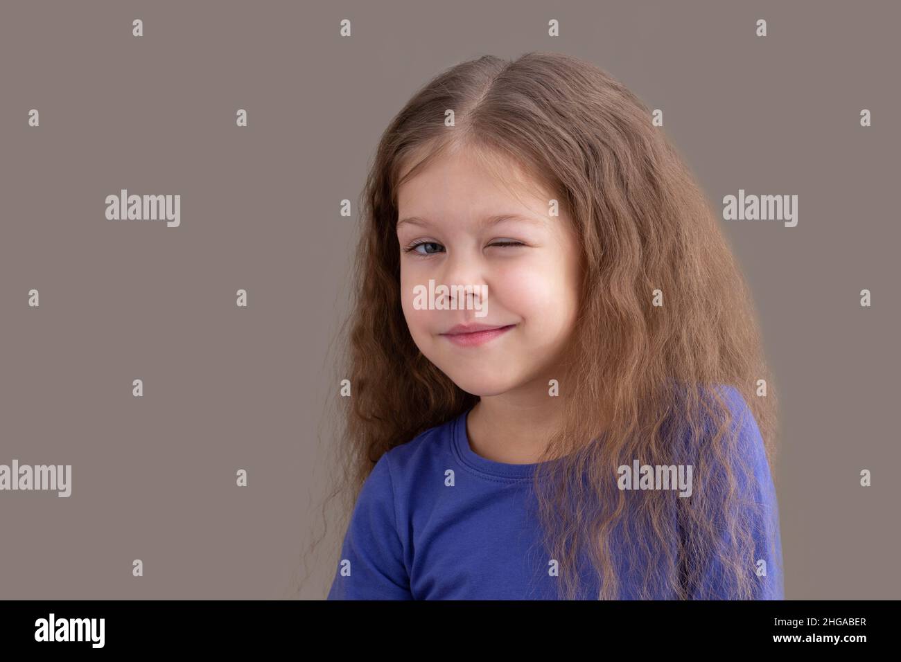 Winking child kid on brown background looking at camera portrait of ...