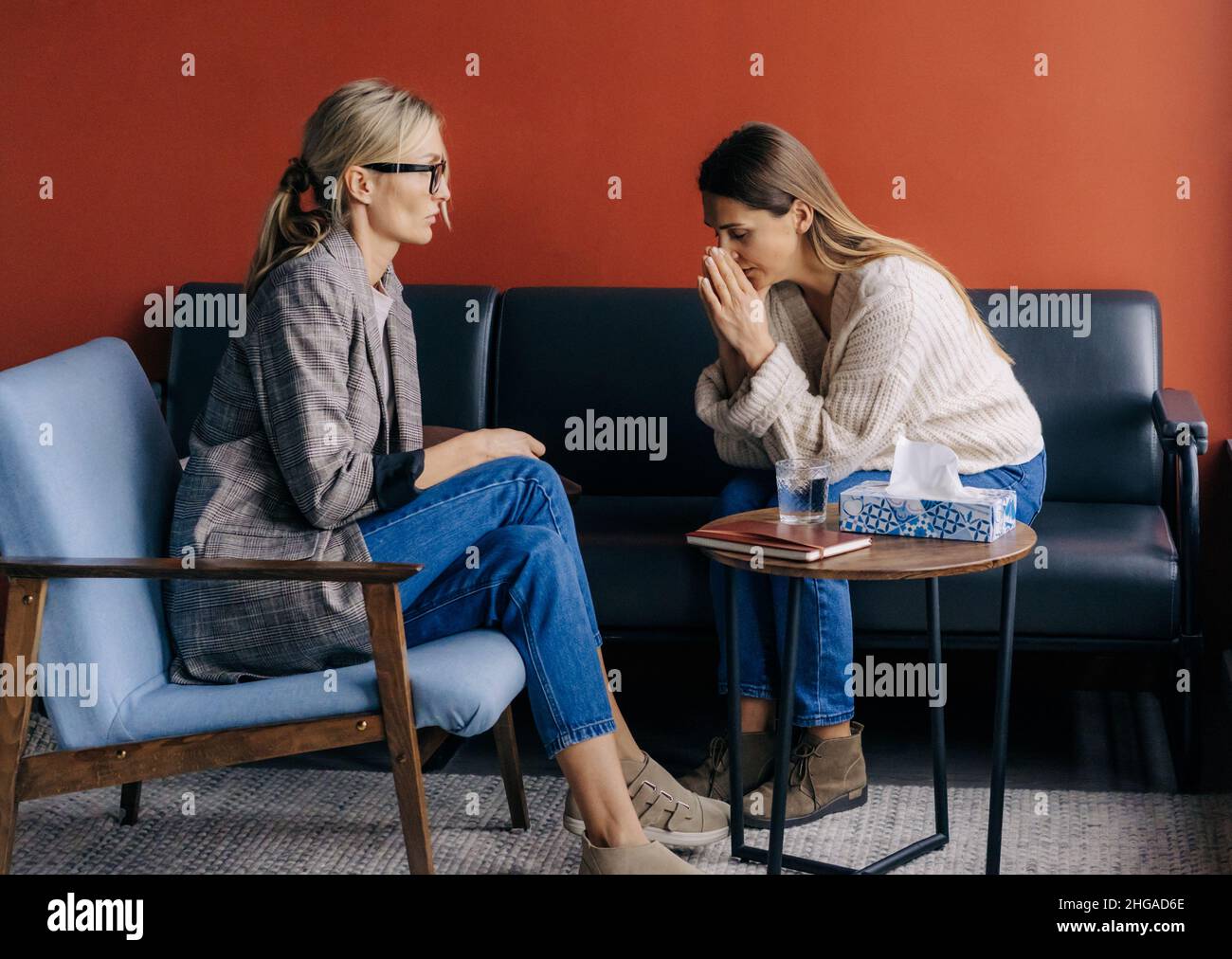 Crying depressed female client sitting on couch in therapist's workshop ...