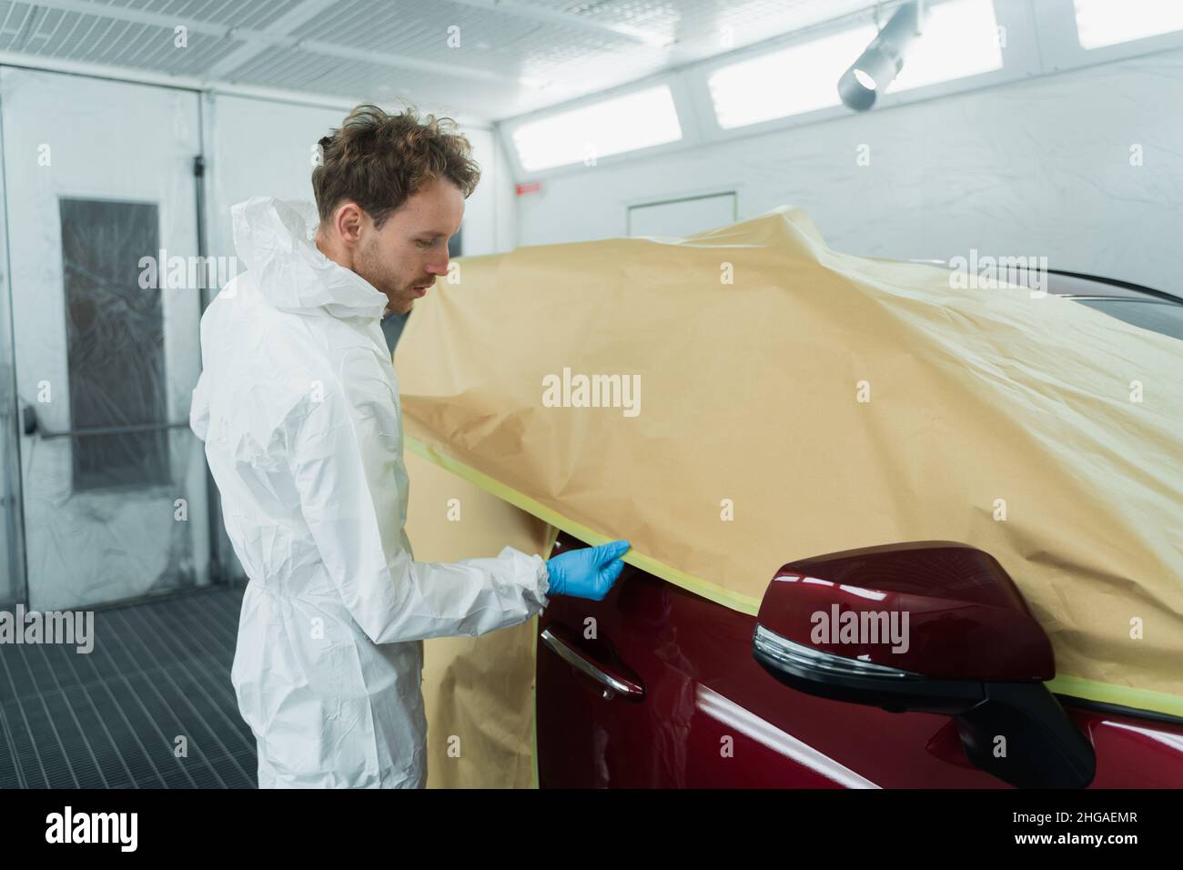 Auto painter covering car with paper before painting or polishing in ...