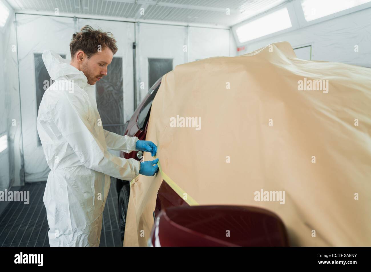 Auto painter masking car with paper before painting or polishing in ...