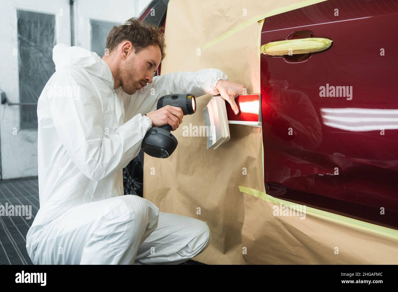 Auto painter compares car body color with colour on samples. Man with a ...