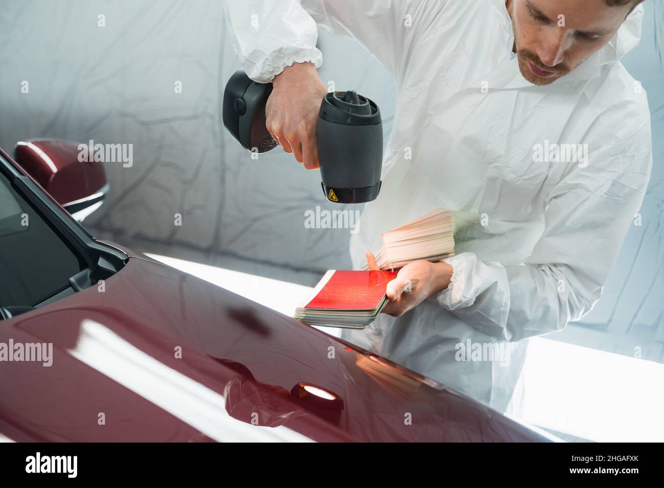 Car painter man determines the correct tone of a vehicle body colour ...