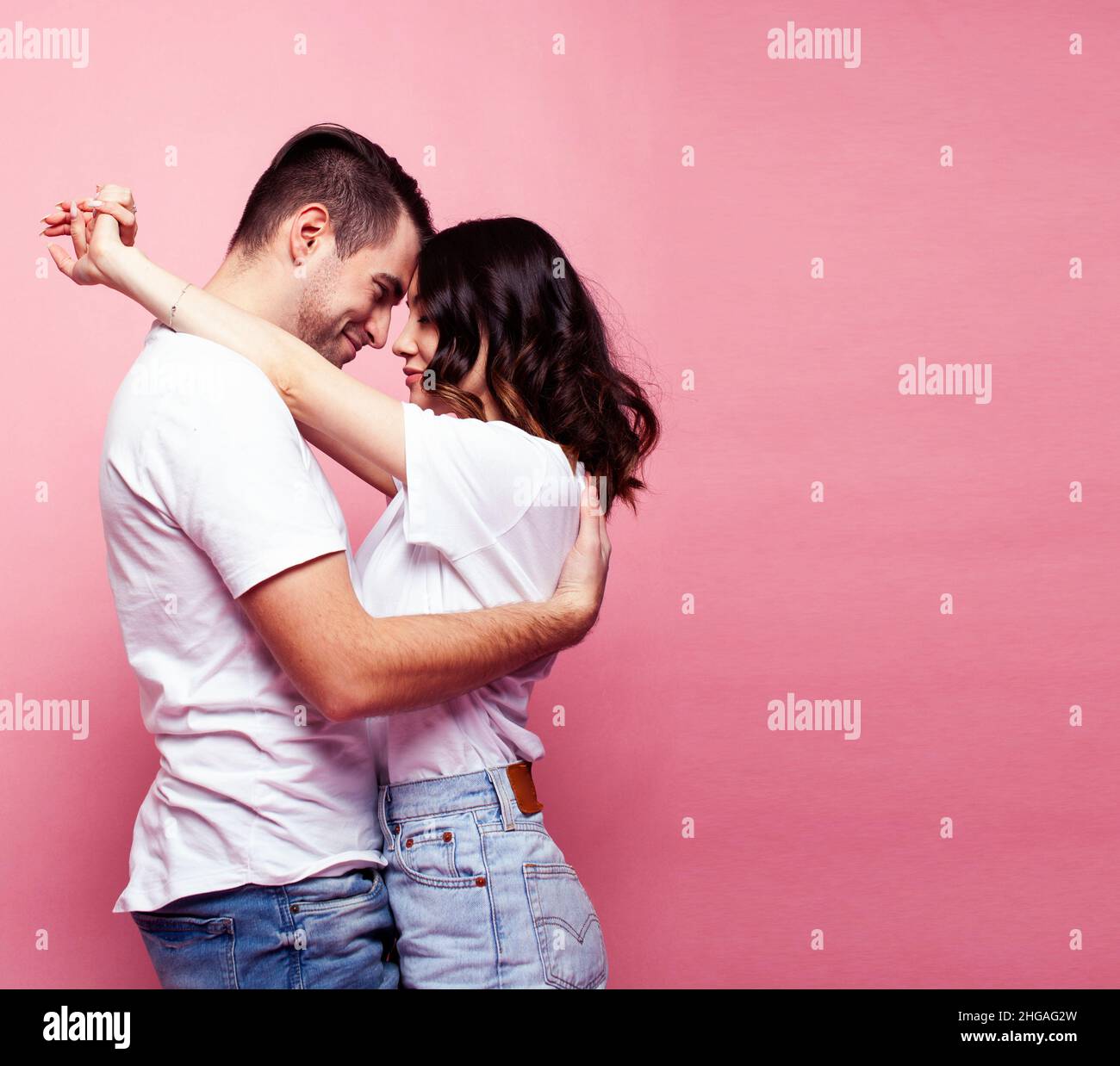 young cheerful caucasian couple together having fun on pink background ...