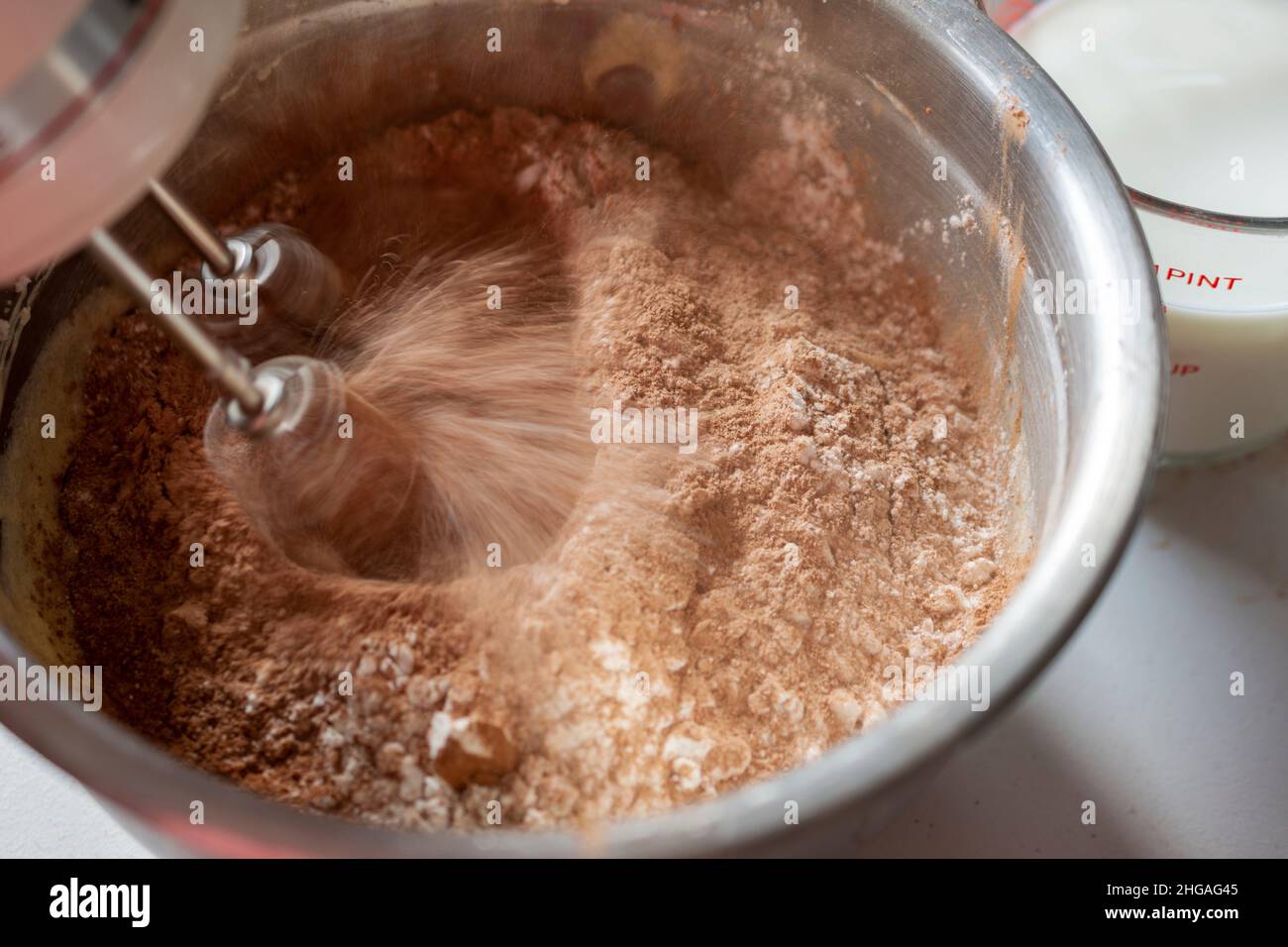 Making of a chocolate cake: Adding dry ingredients. Mixer beaters in ...