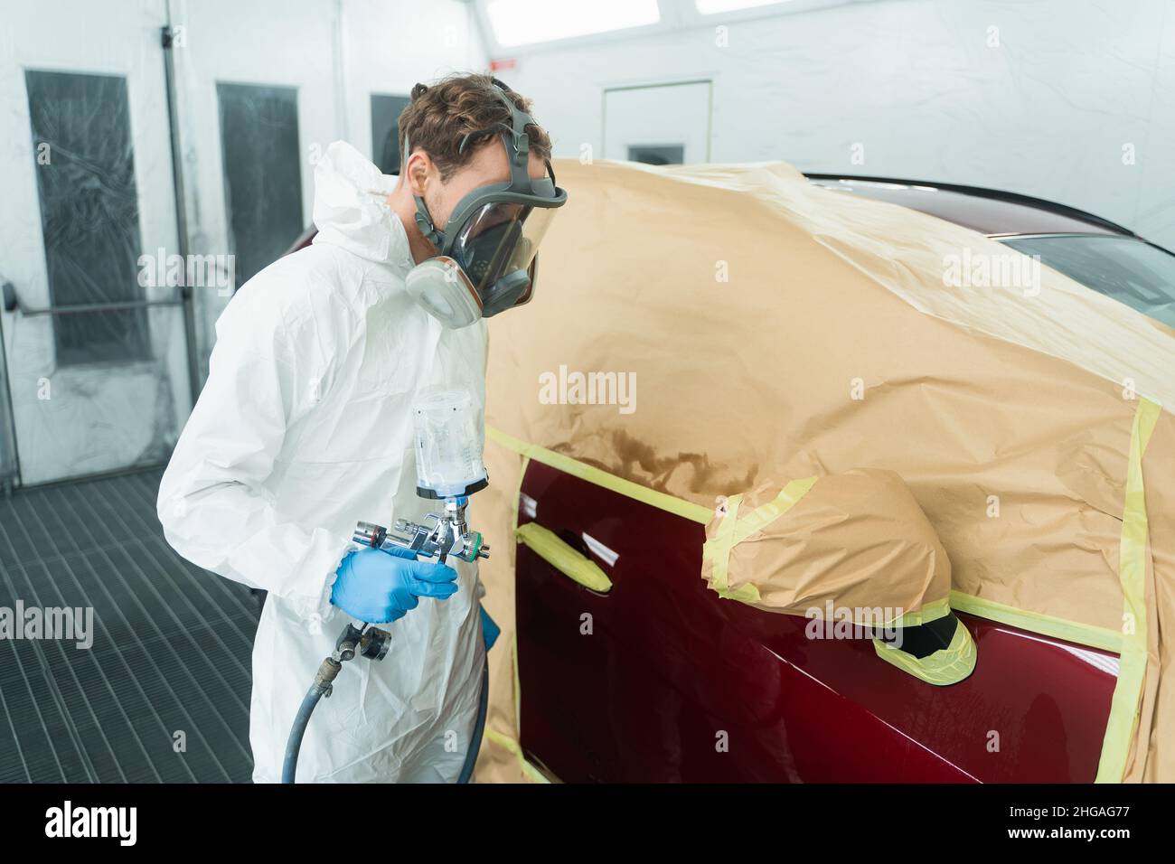 Auto painter with spray gun in car painting booth Stock Photo - Alamy