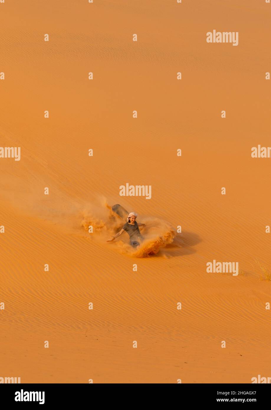 Tourist making sandboarding in the Rub al Khali dunes desert, Najran ...