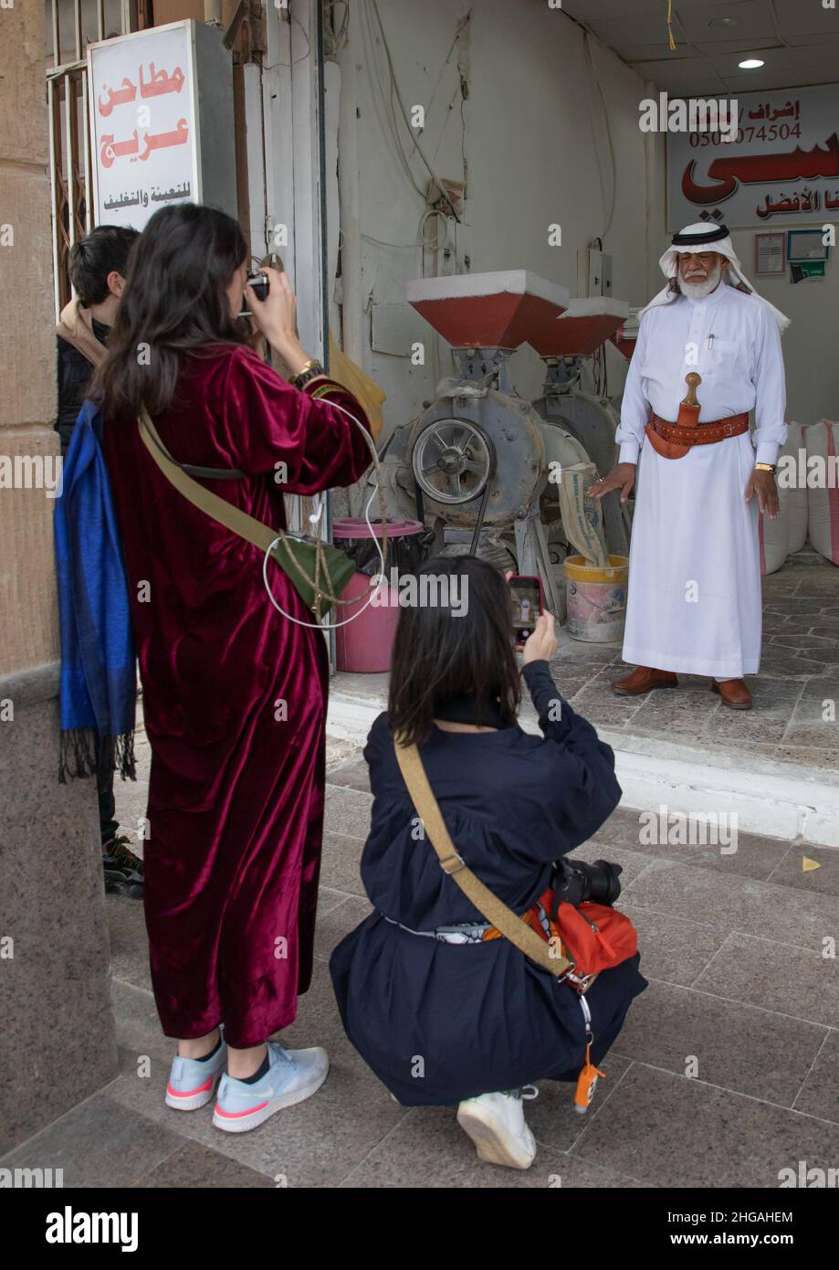 Tourists taking pictures of a saudi man with the traditional janbiya ...