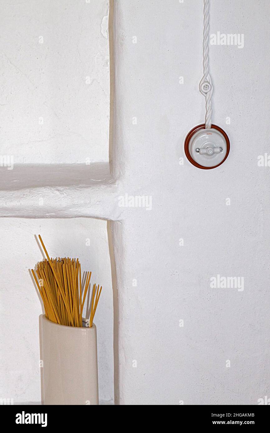 Spaghetti noodles in white container in front of white wall with old ...
