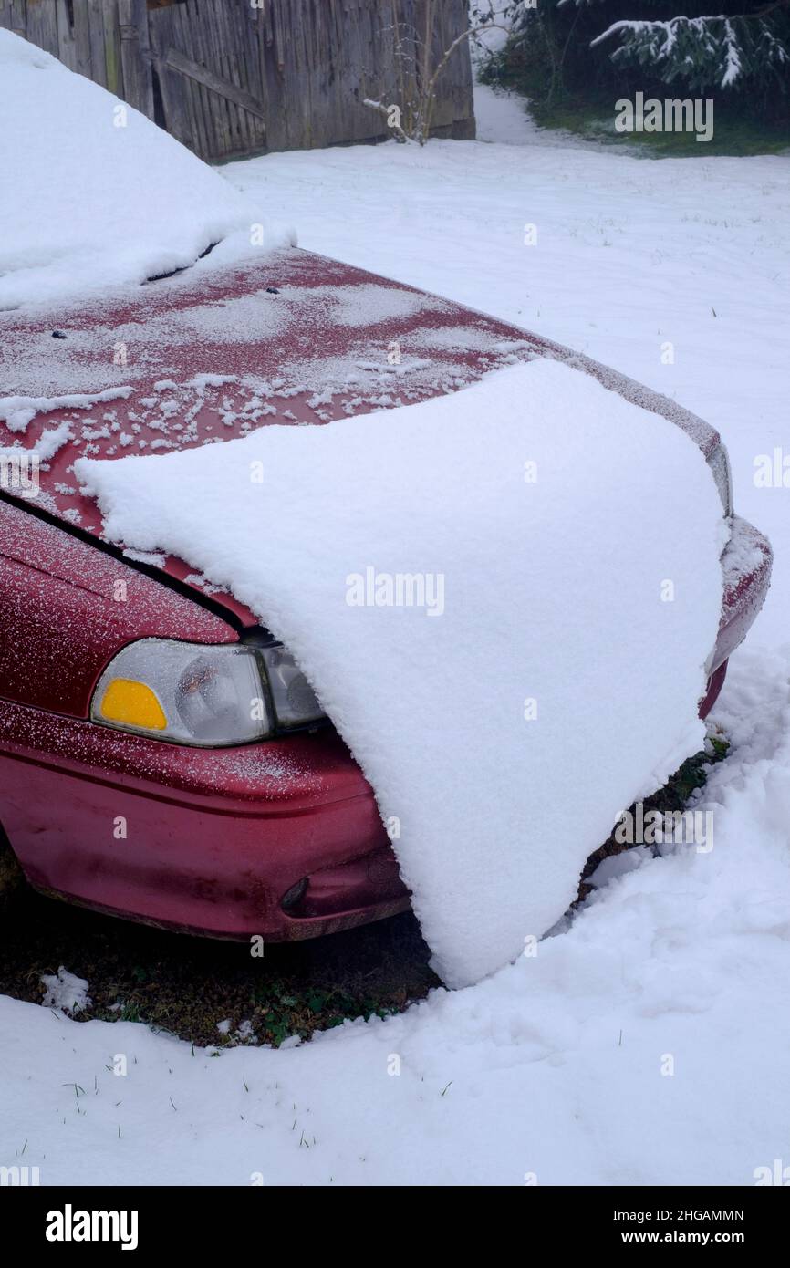 blanket of snow that has partially thawed and slid down car bonnet ...
