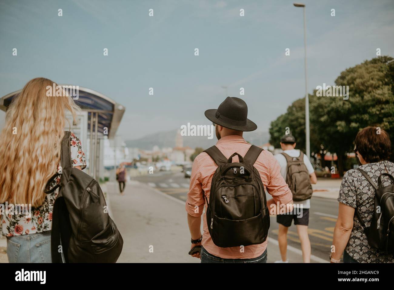 A group of people walks around the city, tourists with backpacks ...