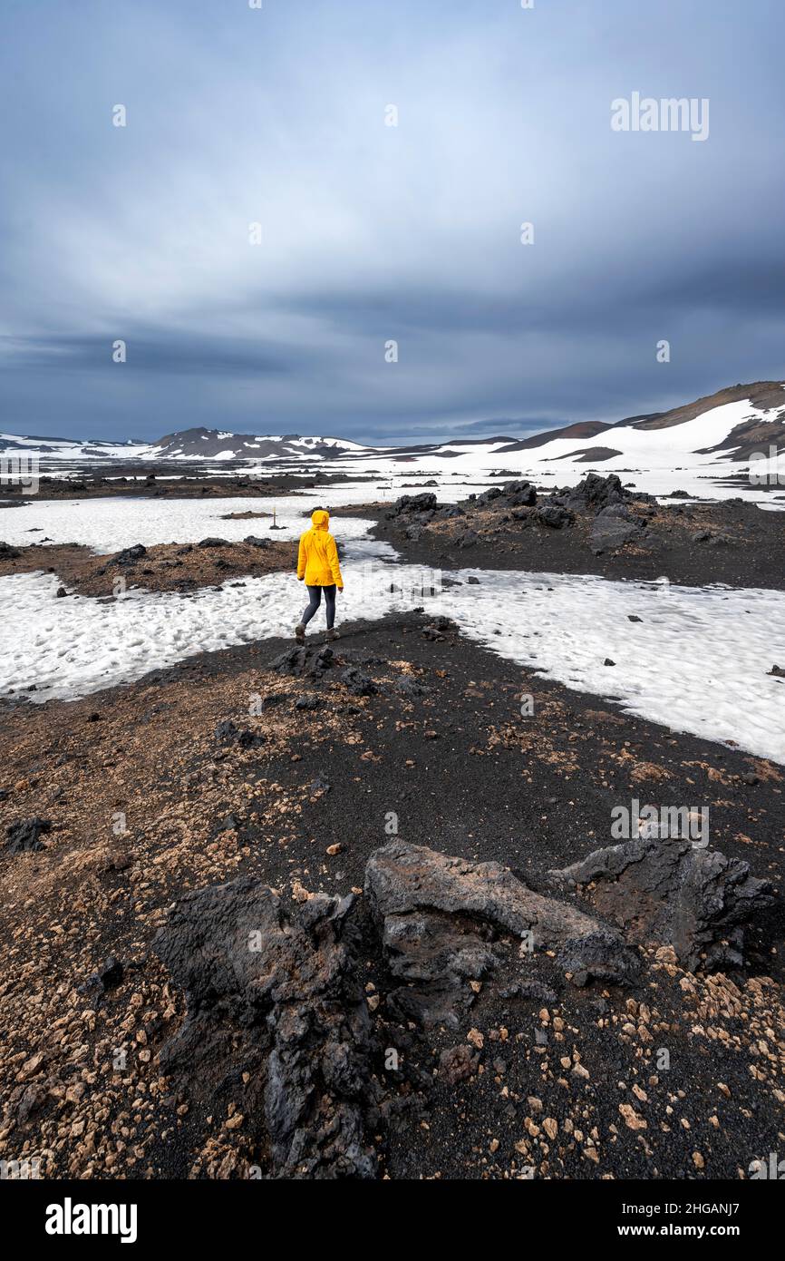Hiker in the crater of the Askja volcano, snow-covered volcanic ...