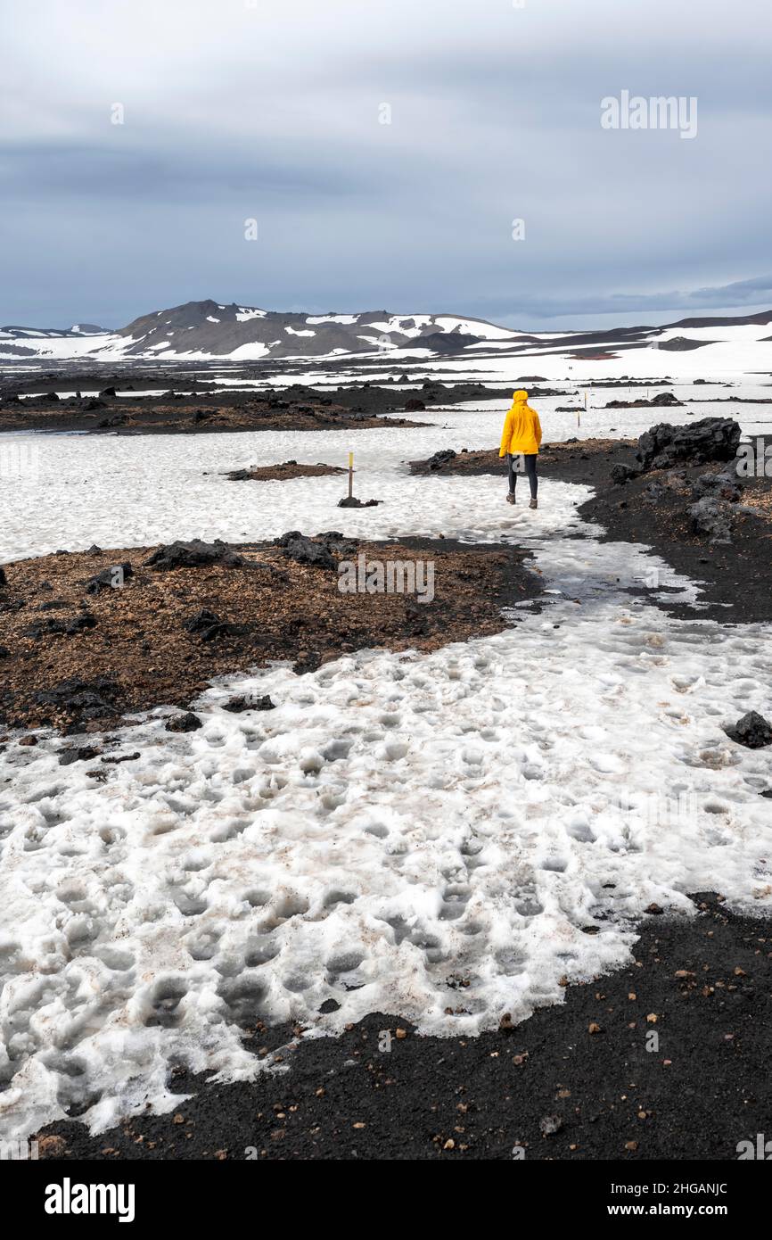 Hiker in the crater of the Askja volcano, snow-covered volcanic ...