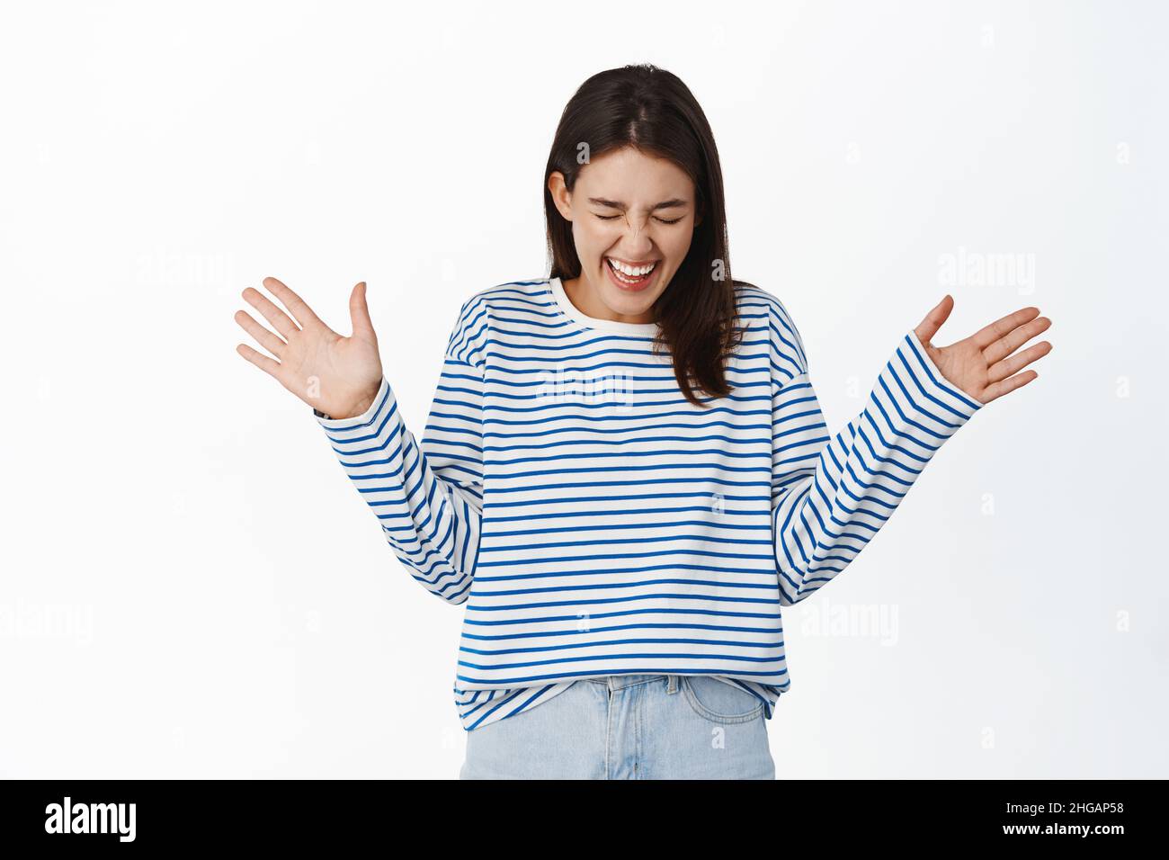Portrait of excited brunette girl laughing and smiling, raising hands ...