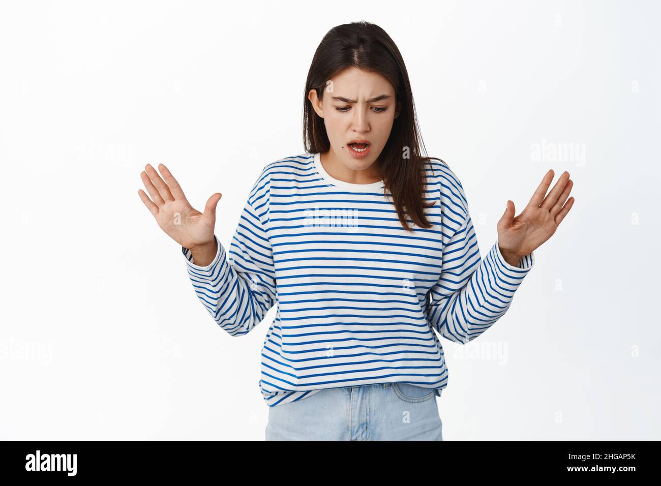 Image of shocked startled woman raising hands up, looking down, drop ...
