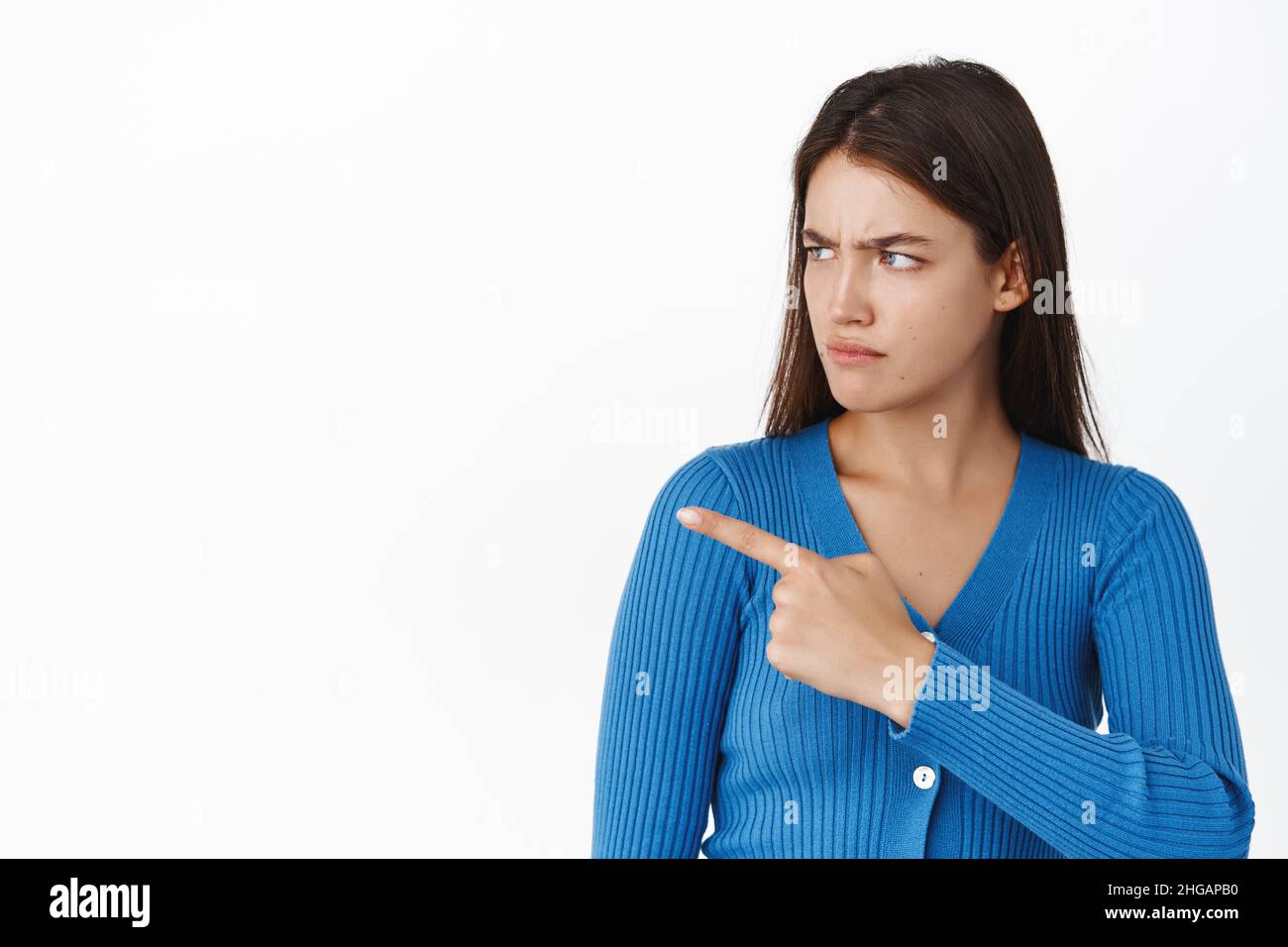 Close up of angry brunette woman in blue blouse, frowning with concern ...
