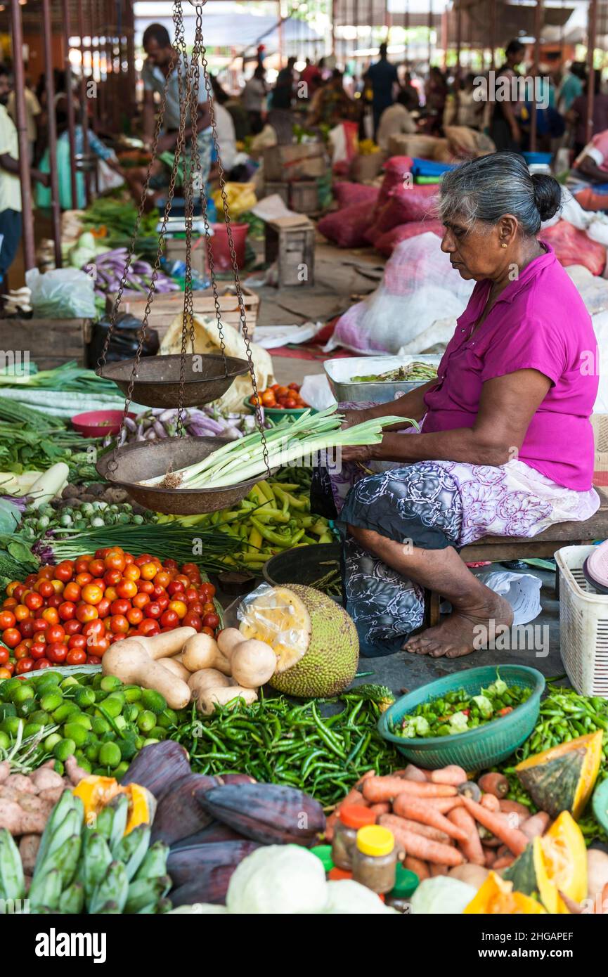 Market, market stall in market hall, market woman weighing vegetables in scales, Tangalle ...