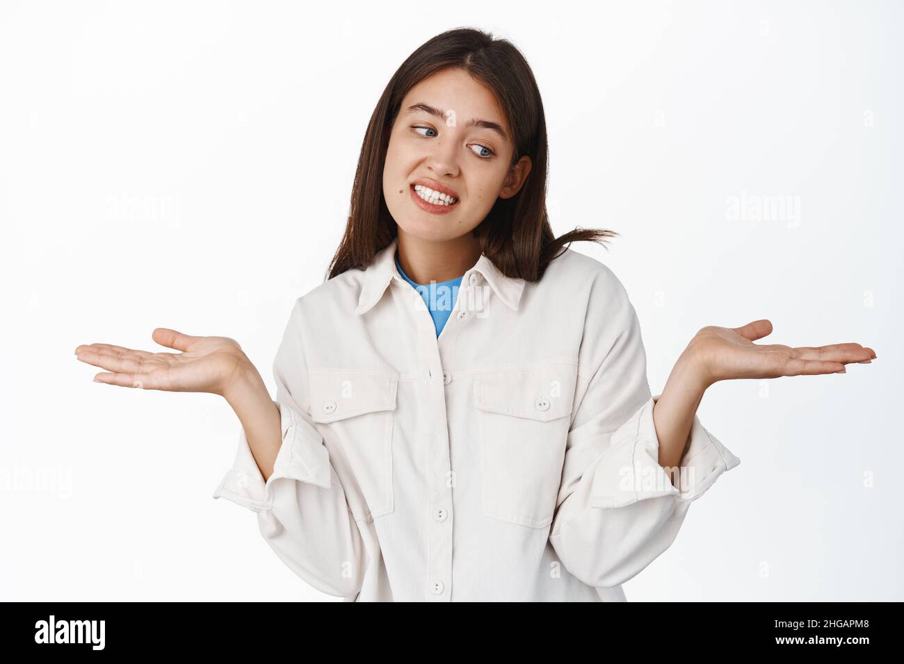 Image of cute silly student girl, shrugging shoulders and looking away ...