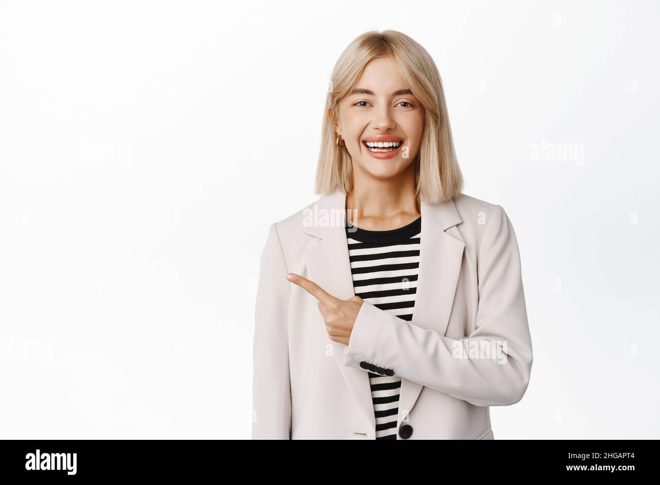 Smiling corporate girl, young businesswoman in suit pointing finger ...