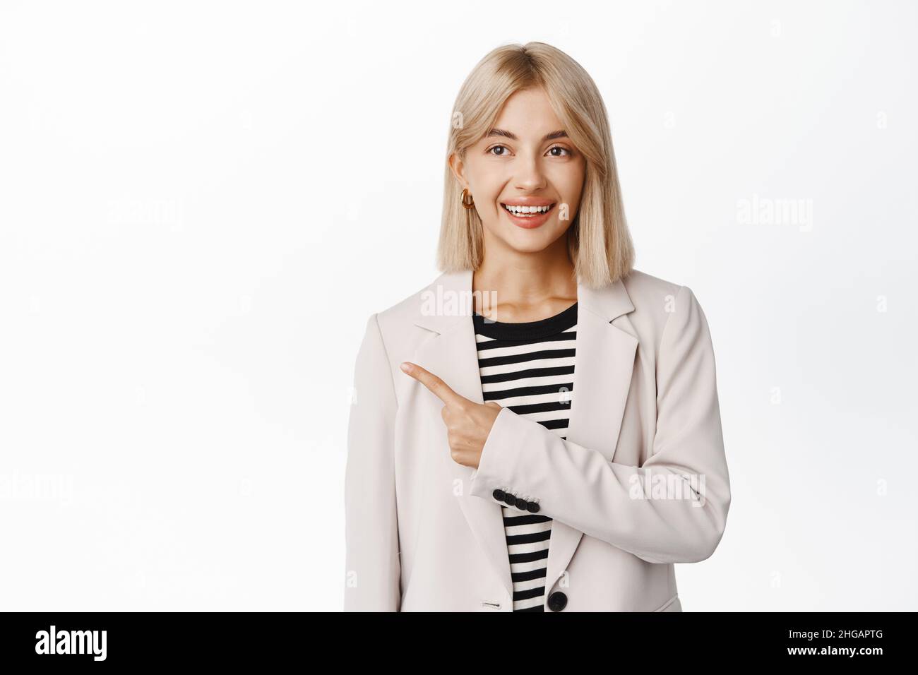 Portrait of smiling corporate girl in beige suit, pointing finger left ...