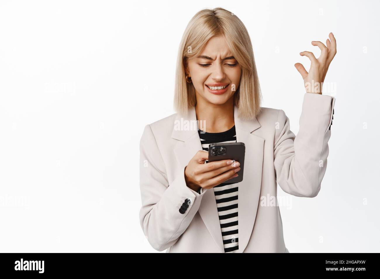 Upset businesswoman looking at mobile phone with regret, sad about ...
