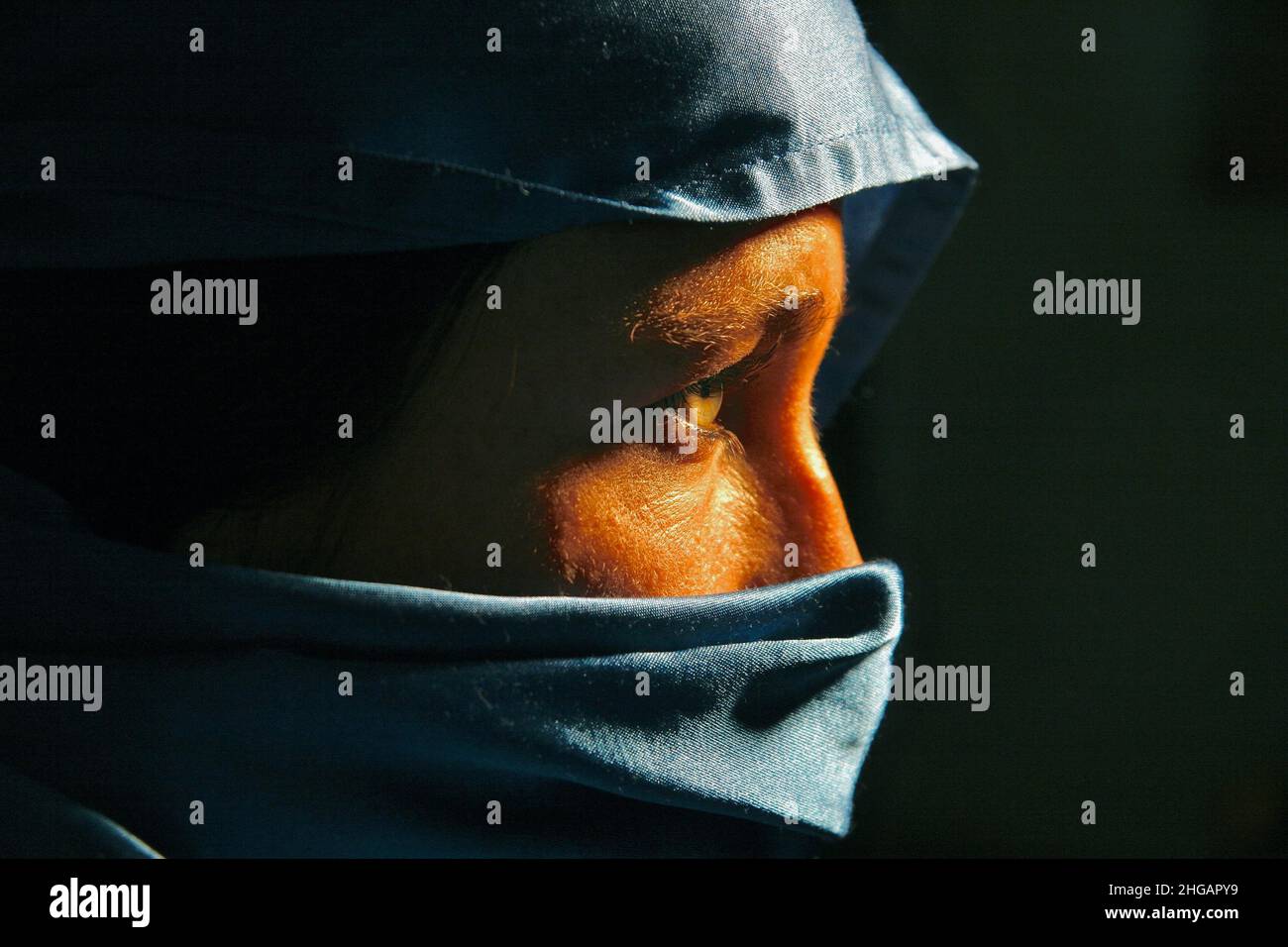 Profile of young woman with blue veil over mouth and nose, Germany ...